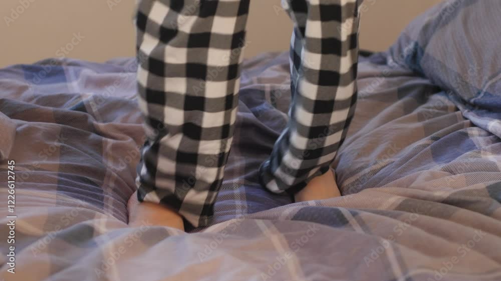 baby happy and playful jumping in bed in pajamas, legs of baby jumping ...