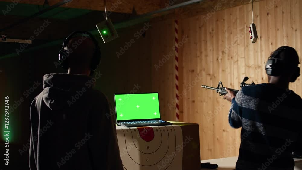 Green screen laptop next to shooting gallery safety officer watching ...