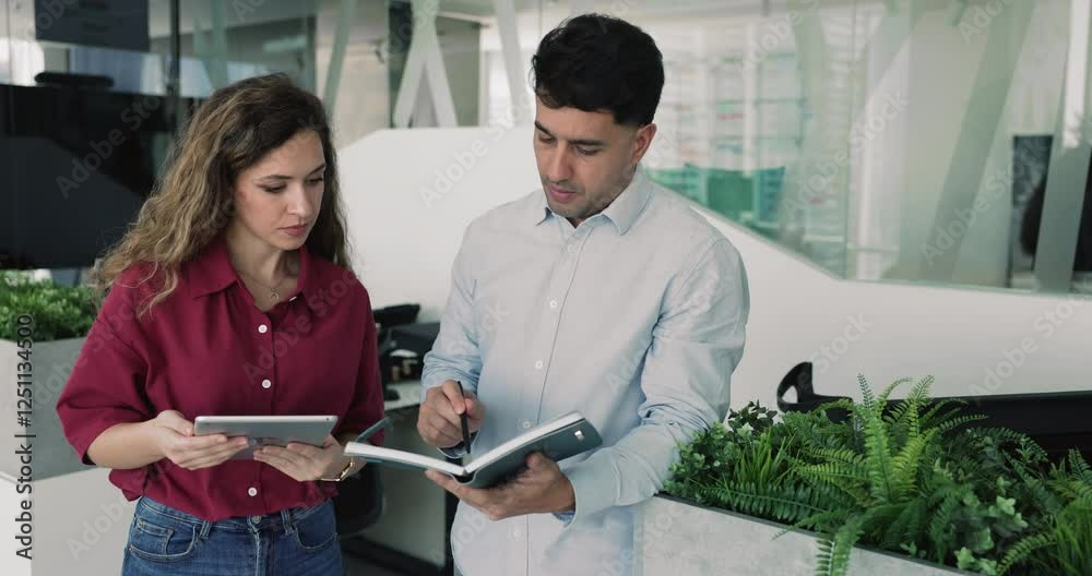 Two young office employees interacting in modern co-working space ...