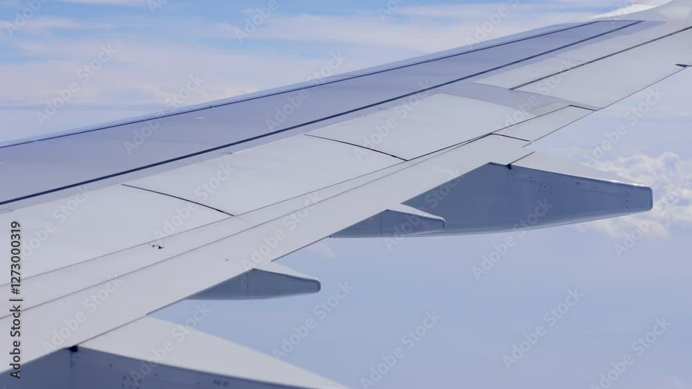 A close-up view of an airplane wing in flight, soaring above the clouds ...
