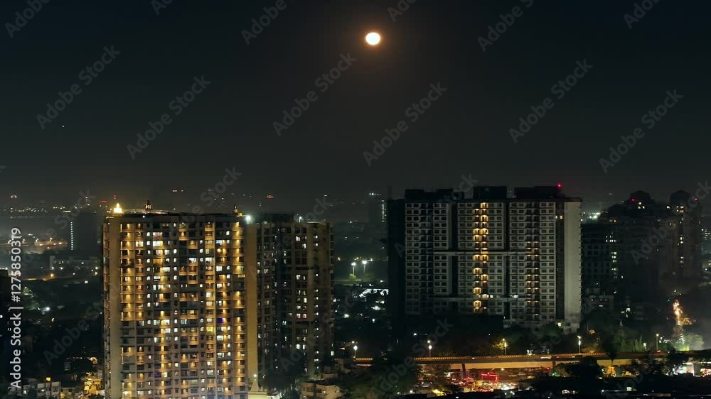 Aerial drone shot moving right over Mumbai city at night with the moon ...