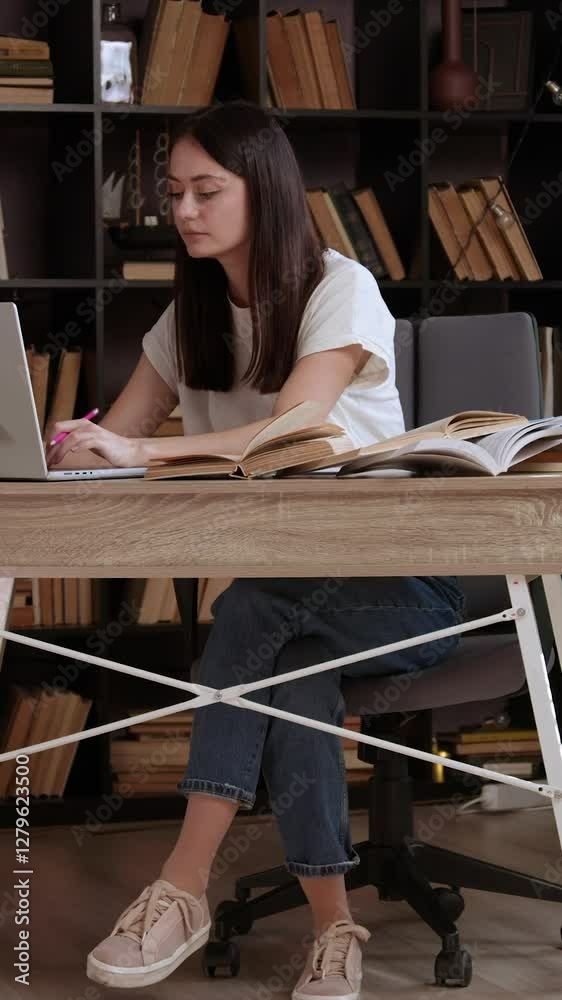 Attractive female student doing homework studying from textbooks while ...