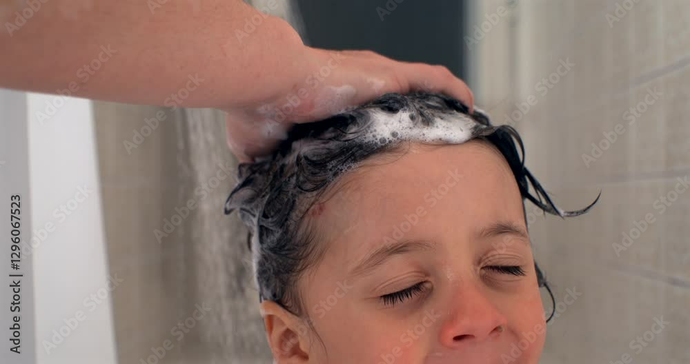 Adult hand gently washing child's hair with shampoo in ultra slow ...