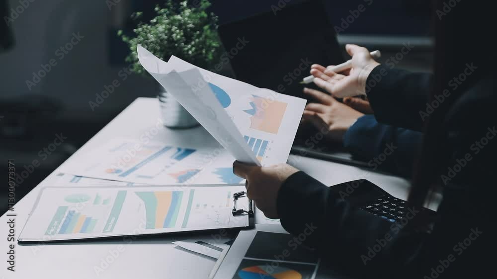 Two Financial analysts examine financial charts and graphs together ...