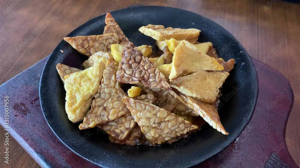 Tahu dan tempe goreng renyah disajikan di meja bersama sambal dan hot ...