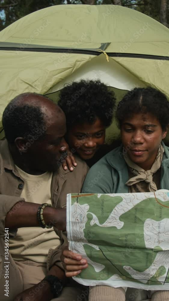 Vertical view of dad and daughter studying map and speaking with each ...