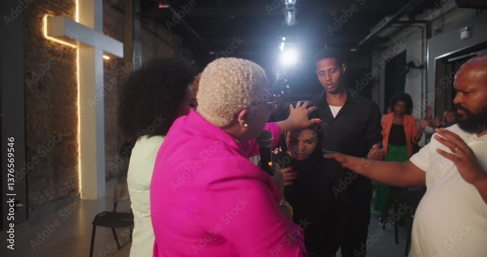 Group of people engaged in spiritual prayer, laying hands on a woman in ...