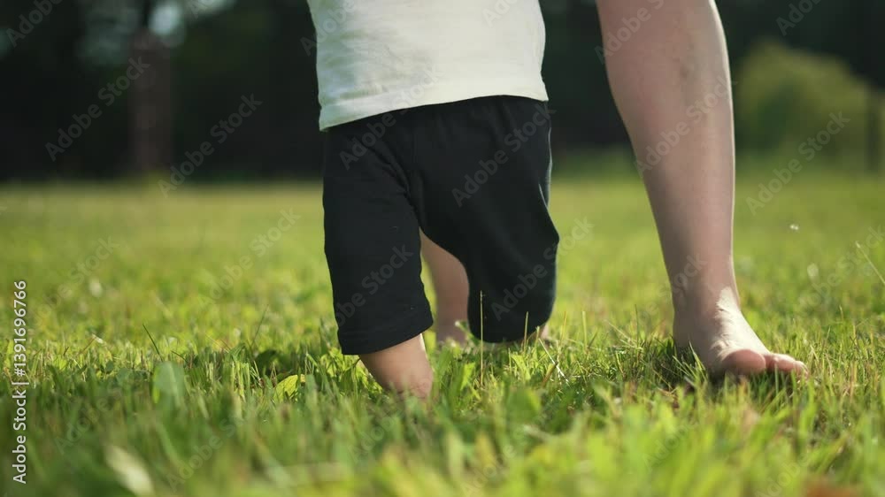 Happy family helps child walk. Mom supports toddler first steps on ...