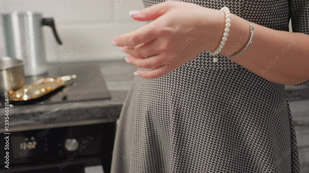 Culinary artist folds kitchen towel with both hands, wearing elegant ...