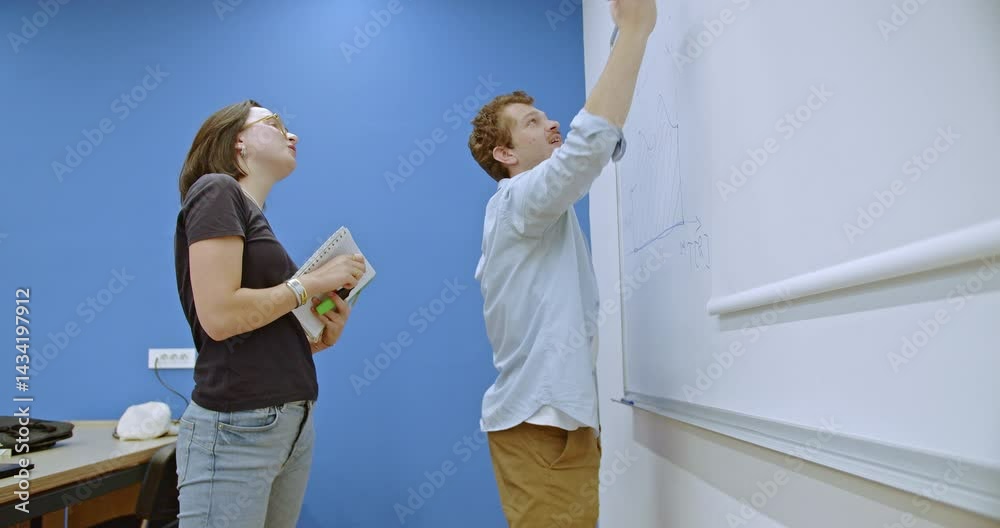 Students collaborate on a project, drawing diagrams and formulas on a ...