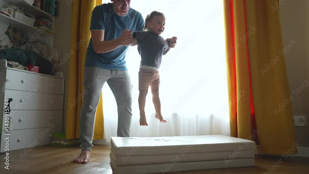 Father lifts son up jumping. Baby jumps on mattress with father. Happy ...