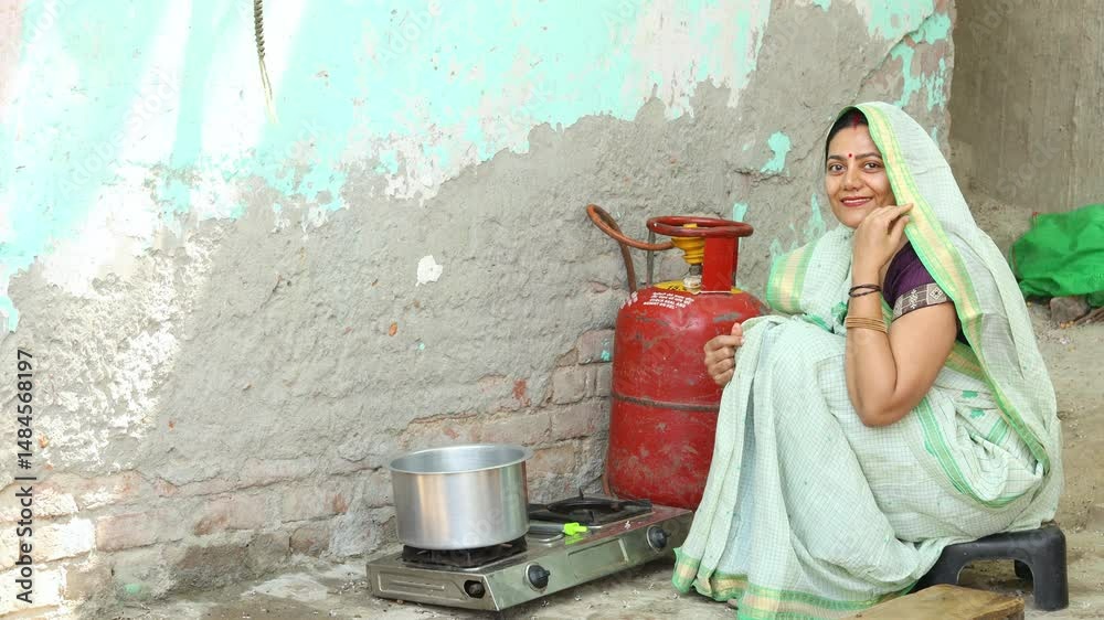Rural Indian woman cooking in kitchen with LPG Gas Cylinder..People in ...