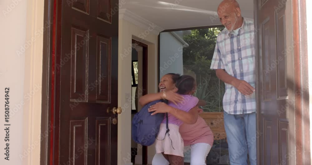 Diverse grandparents hugging granddaughter at home, sharing love and ...
