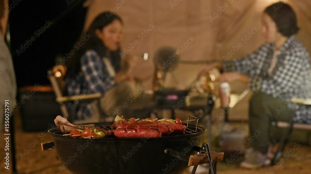 Close-up barbecue grill full of skewers, pork steak and sausage over campfire at night camp ...