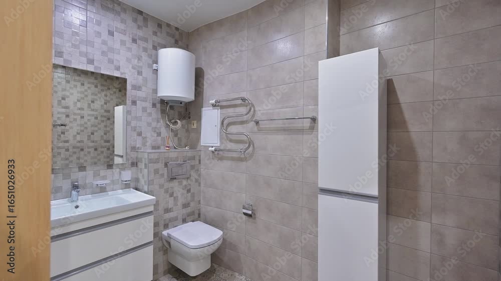 well-lit bathroom features gray tile walls, a white sink and cabinet, a ...