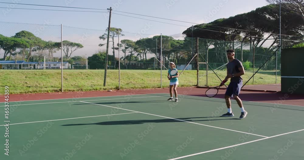 Tossing ball prompting Asian man and White woman partners volleying for ...