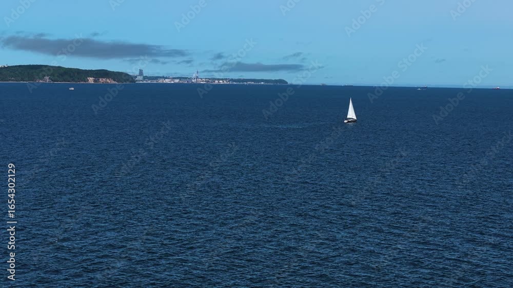 Seascape with sailing yacht and inflatable boat floating on open water ...