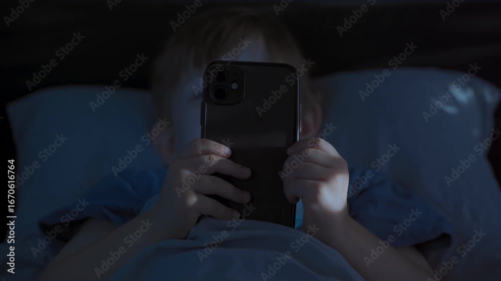 Close-up of unrecognisable little child lying in bed at night, holding ...