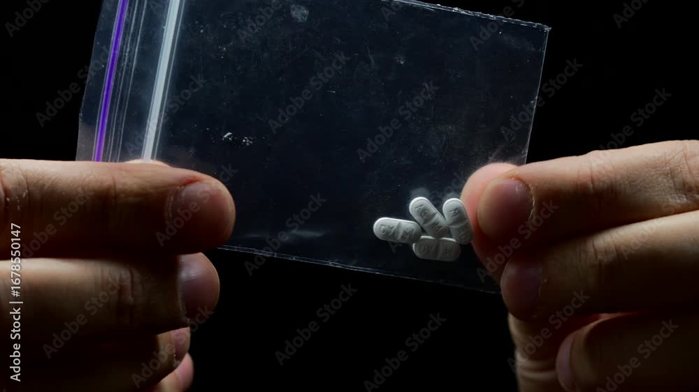 faceless man holding a bag of drugs. LSD and methamphetamine in a ...