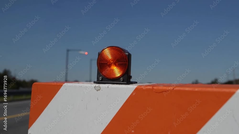 Road barrier with flashing warning light, close-up of an orange warning ...