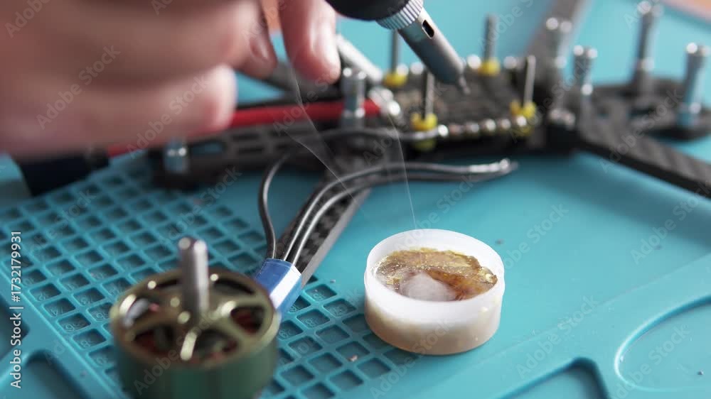 A specialist performs soldering on an FPV drone, attaching power and ...