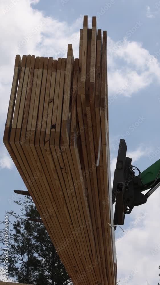 Forklift telehandler crane lifts large wooden truss into place, helping ...