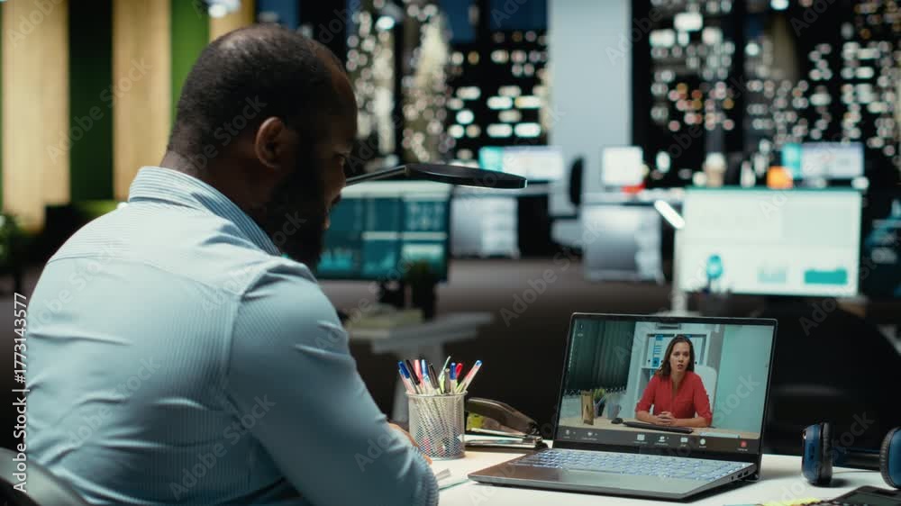 Professional male chatting late at night during online teleconference ...