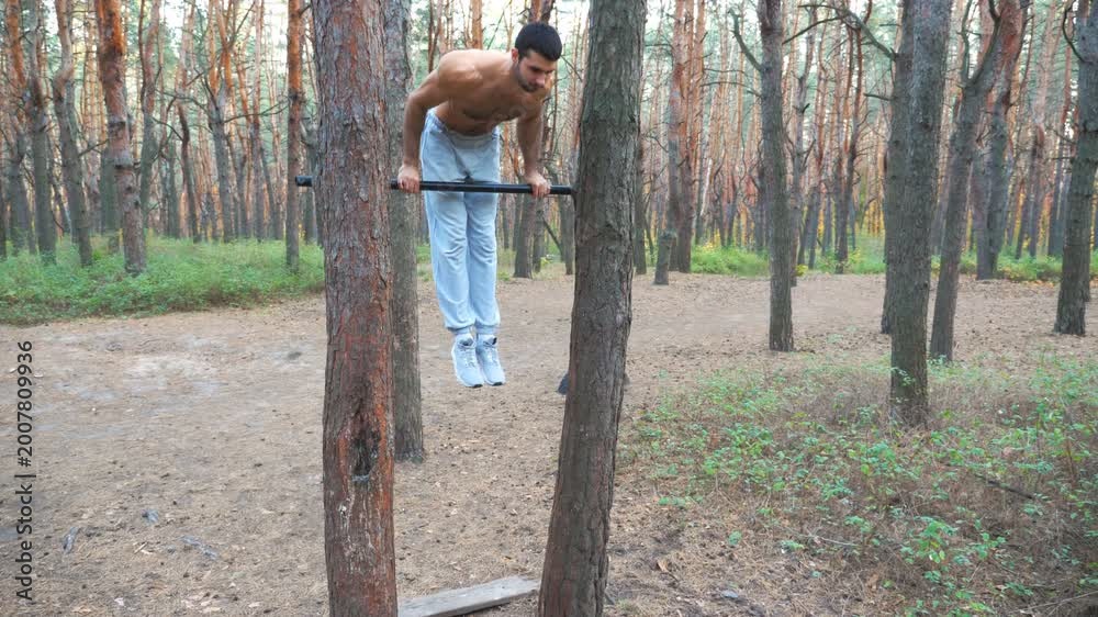 Strong man showing some gymnastics stunts on horizontal bar. Muscular ...