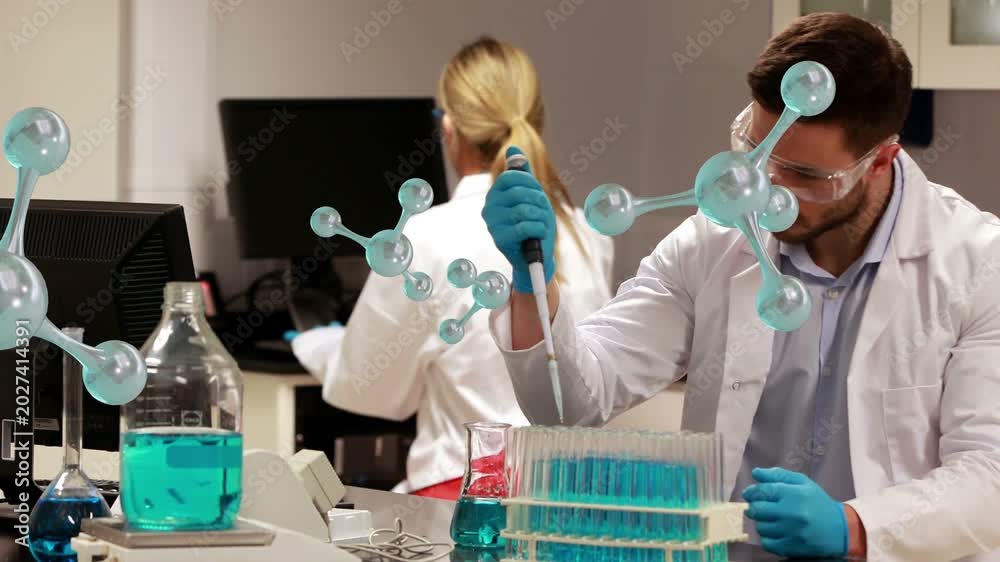 Researcher drawing from flask, pipetting blue liquid into rack for ...
