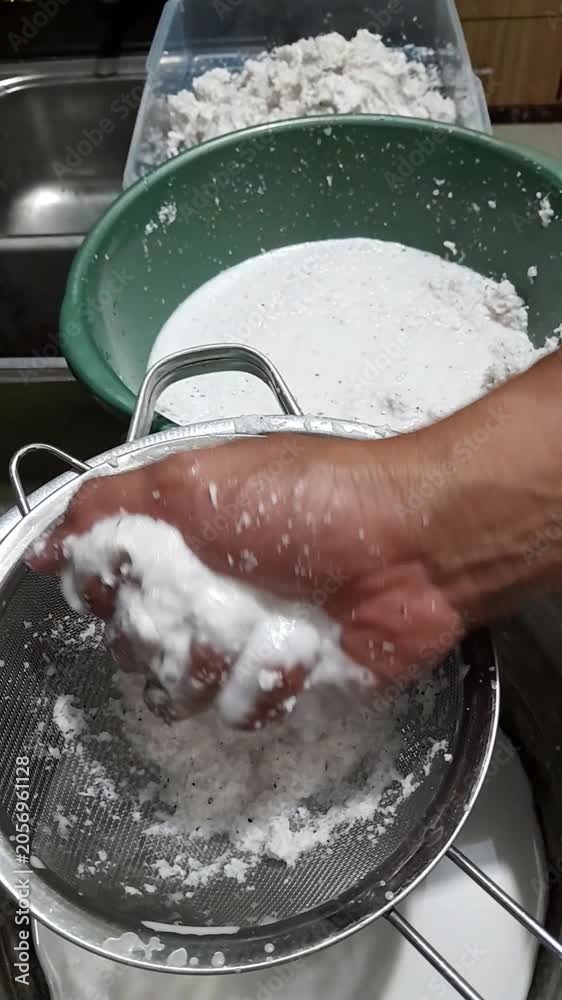 Close-up of a man's hand squeezing grated coconut pulp manually to ...